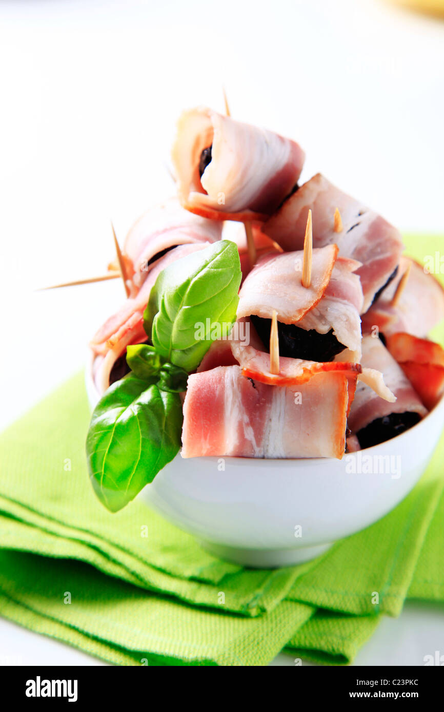 Dried plums wrapped in bacon - studio Stock Photo - Alamy