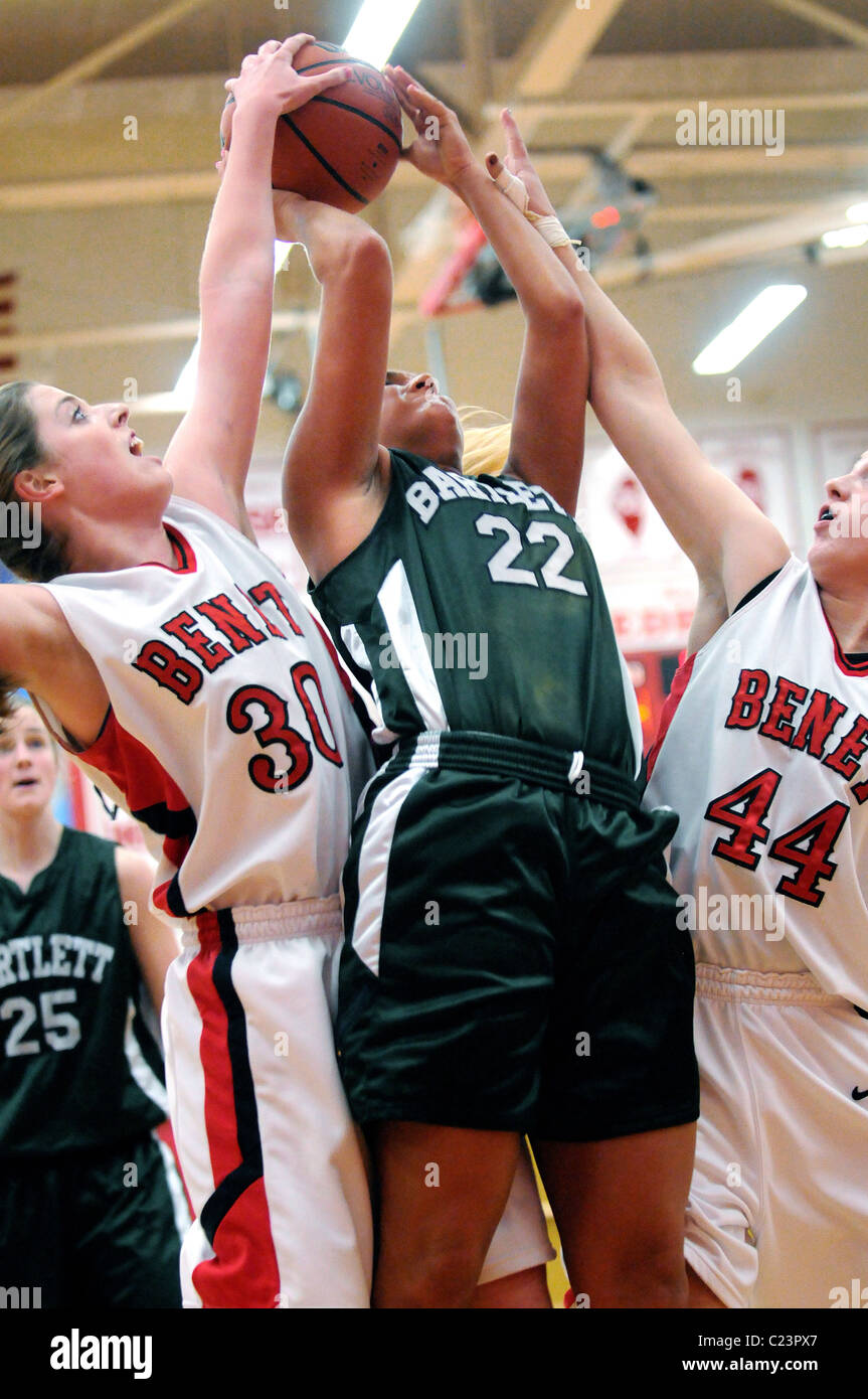 Trio of players fight for a rebound during a high school basketball ...
