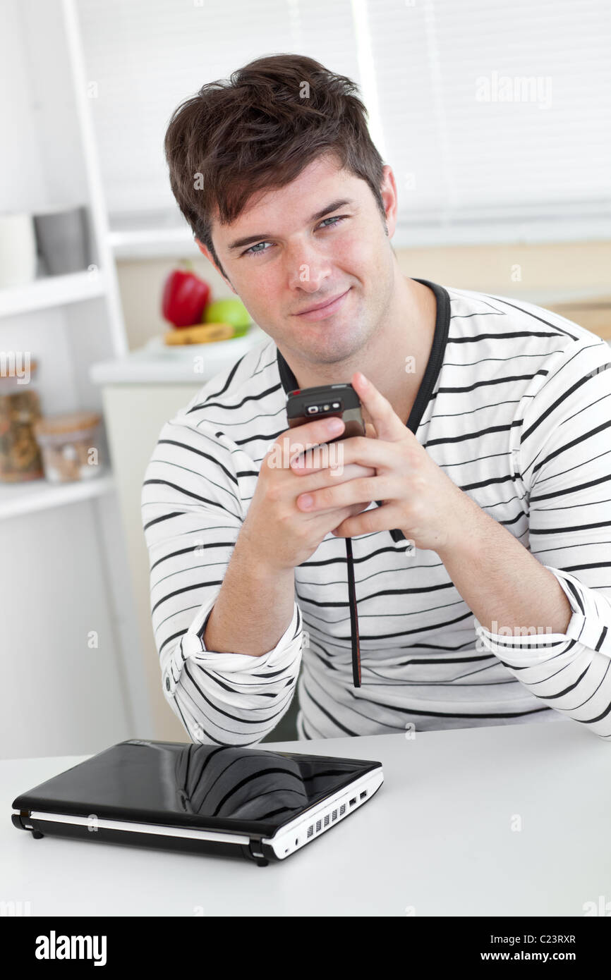 Smiling man sending a text message with his cellphone in front of his ...