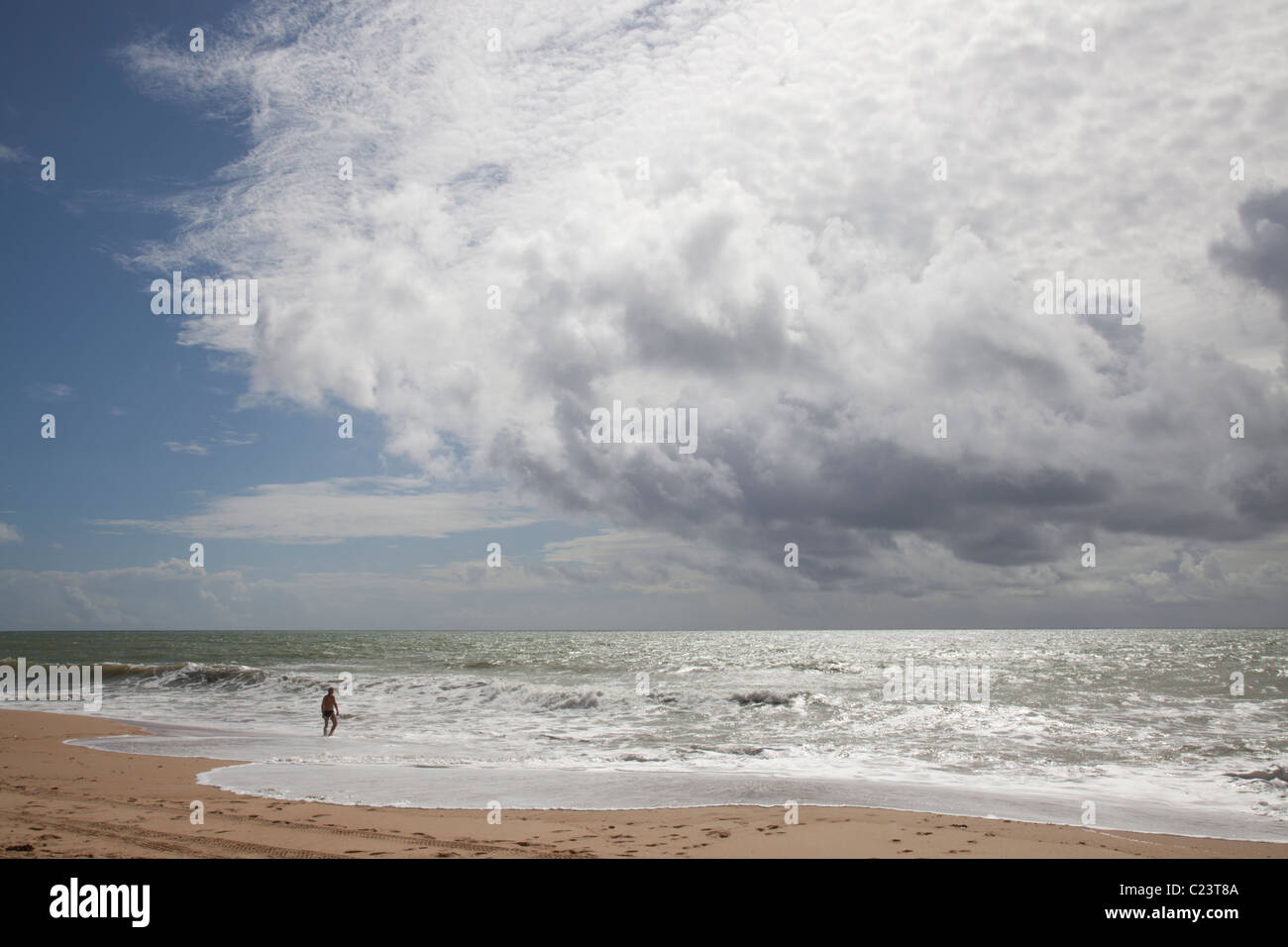Lone figure heading into the sea under a big sky Stock Photo - Alamy