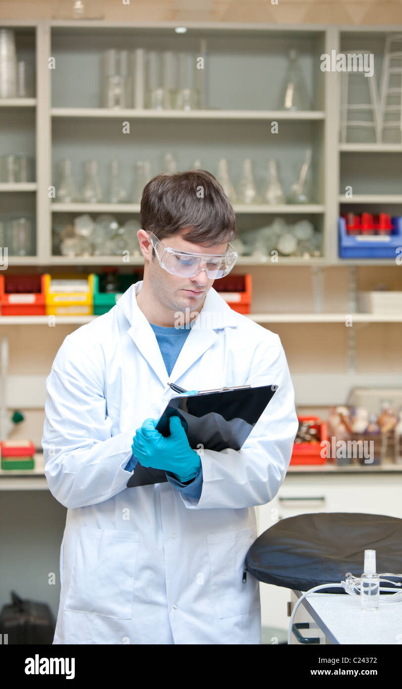 Concentrated male scientist writing on a clipboard Stock Photo - Alamy