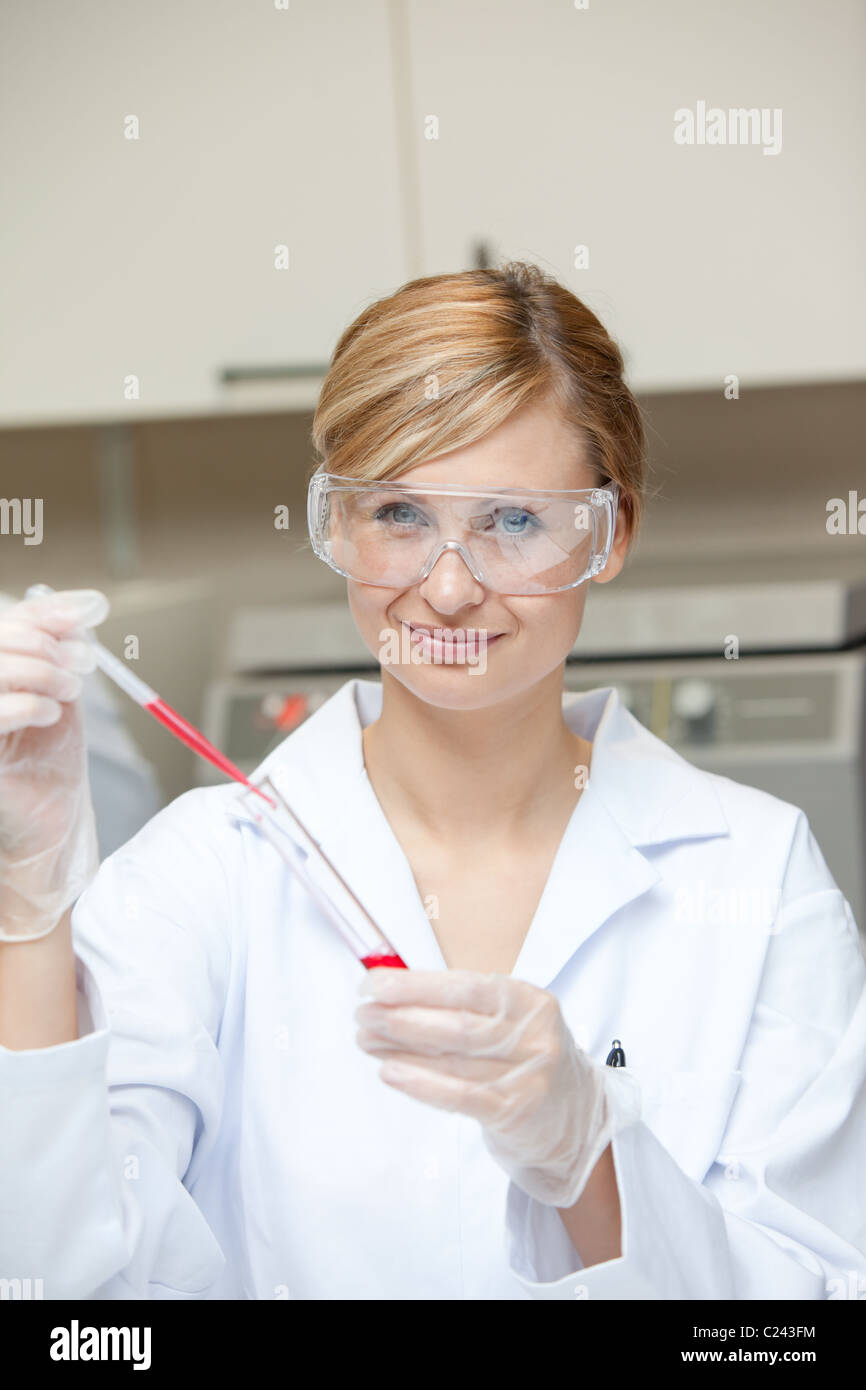 Close-up of a female scientist putting liquid in a test tube with a ...