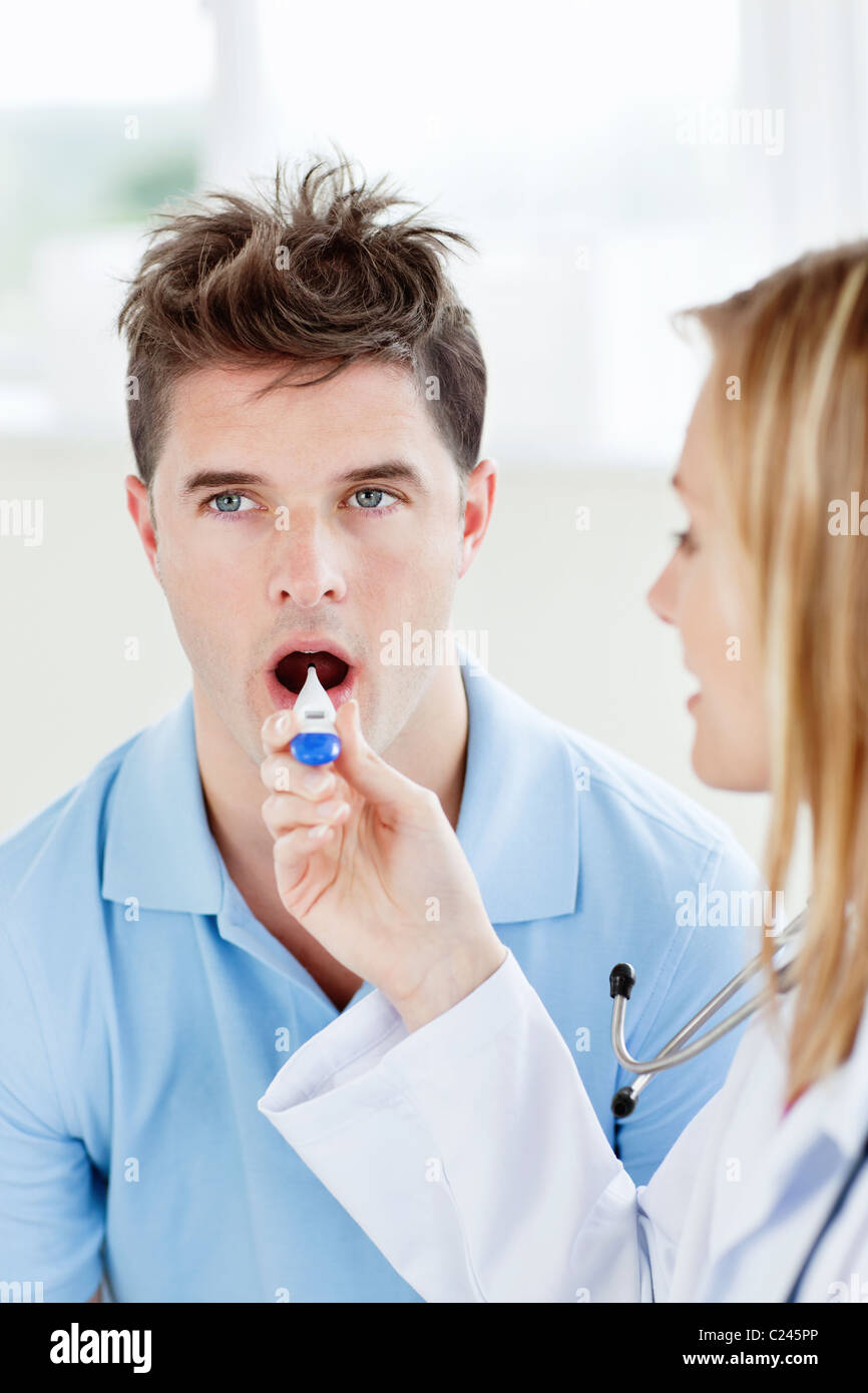 Handsome man with his doctor taking his temperature during an ...