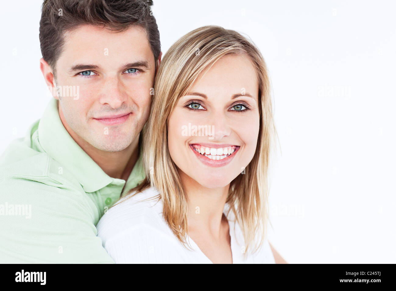 Adorable couple smiling at the camera and standing against a white ...