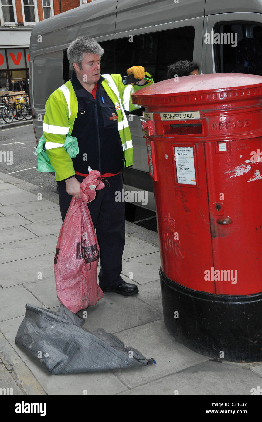 A postman collects post from a postbox in central London after the ...