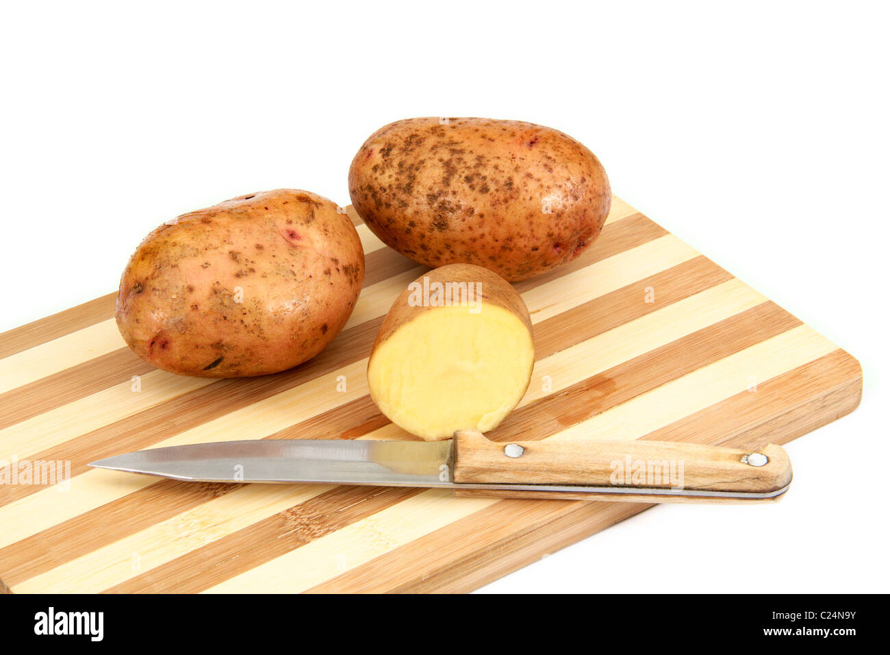 Raw potato tubers lying on a cutting board, isolated on a white ...