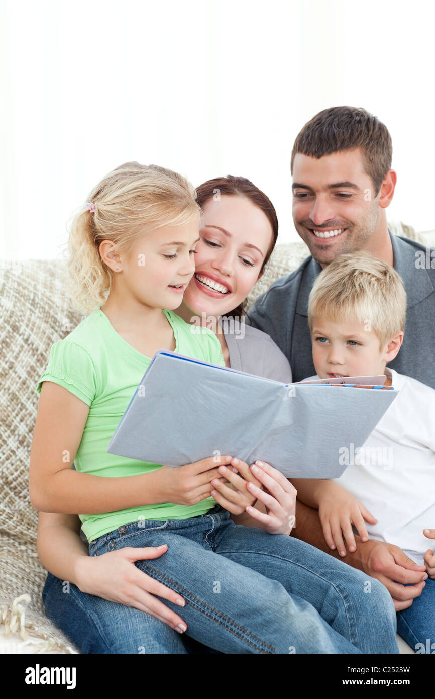 Adorable family reading a book together in the living-room Stock Photo ...