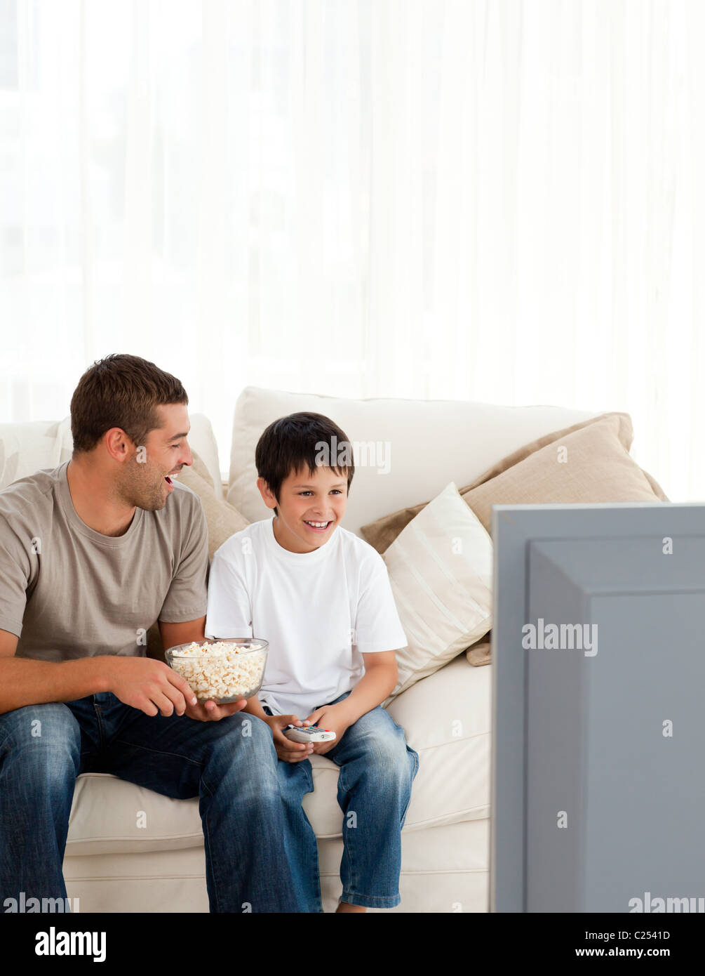 Happy boy watching television with his father on the sofa Stock Photo ...
