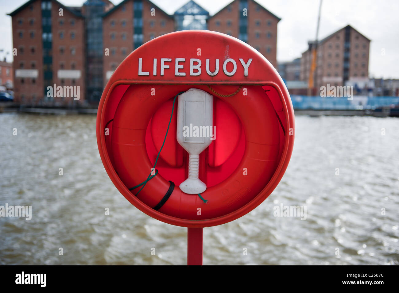 A lifebuoy and holder at the waters edge of a dock Stock Photo - Alamy