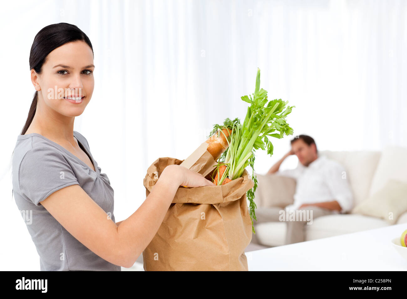 Pretty woman coming back from shopping while her boyfriend relaxing ...