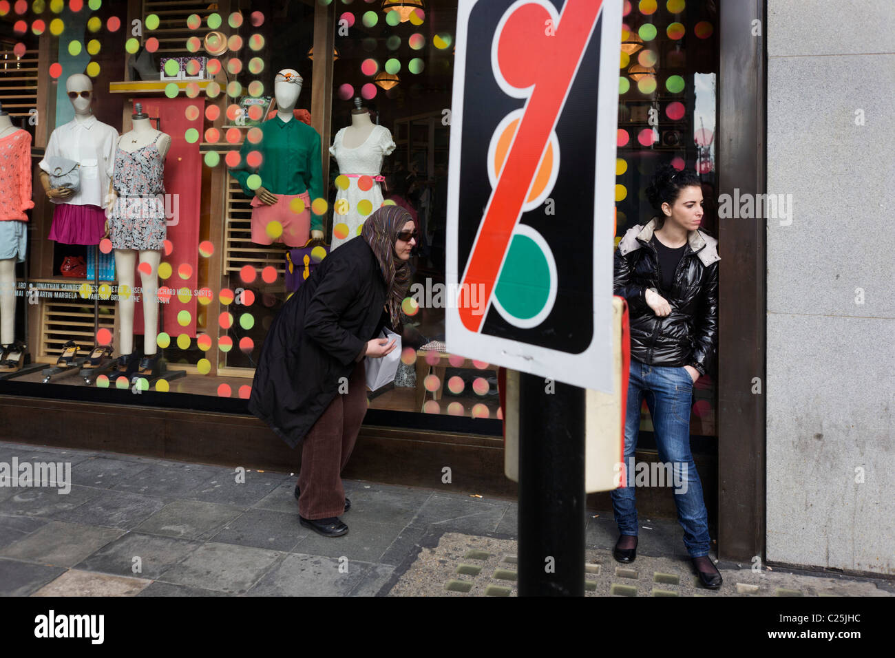 A muslim lady stoops as she walks outside the spotted shop window of ...