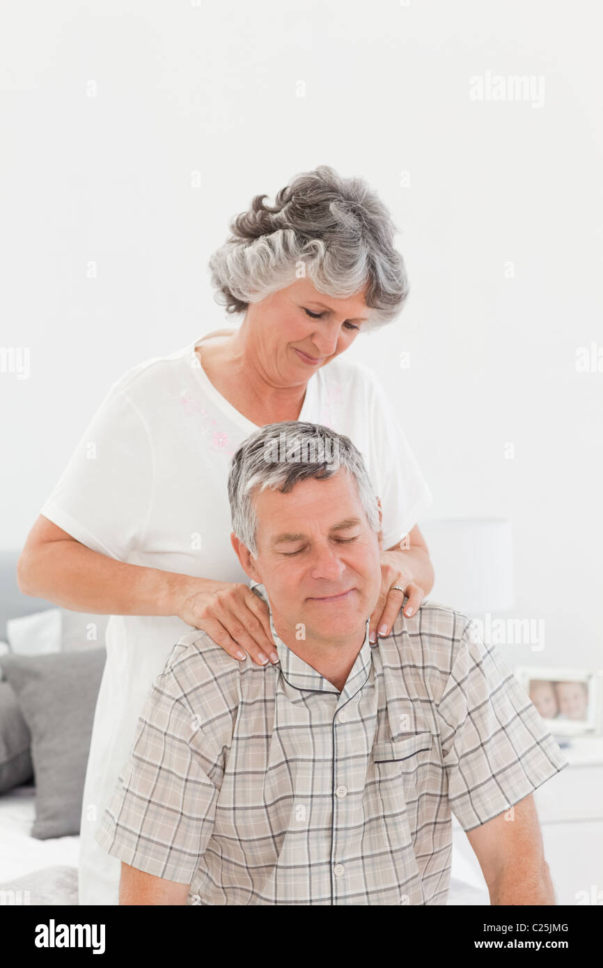 Retired woman giving a massage to her husband at home Stock Photo - Alamy