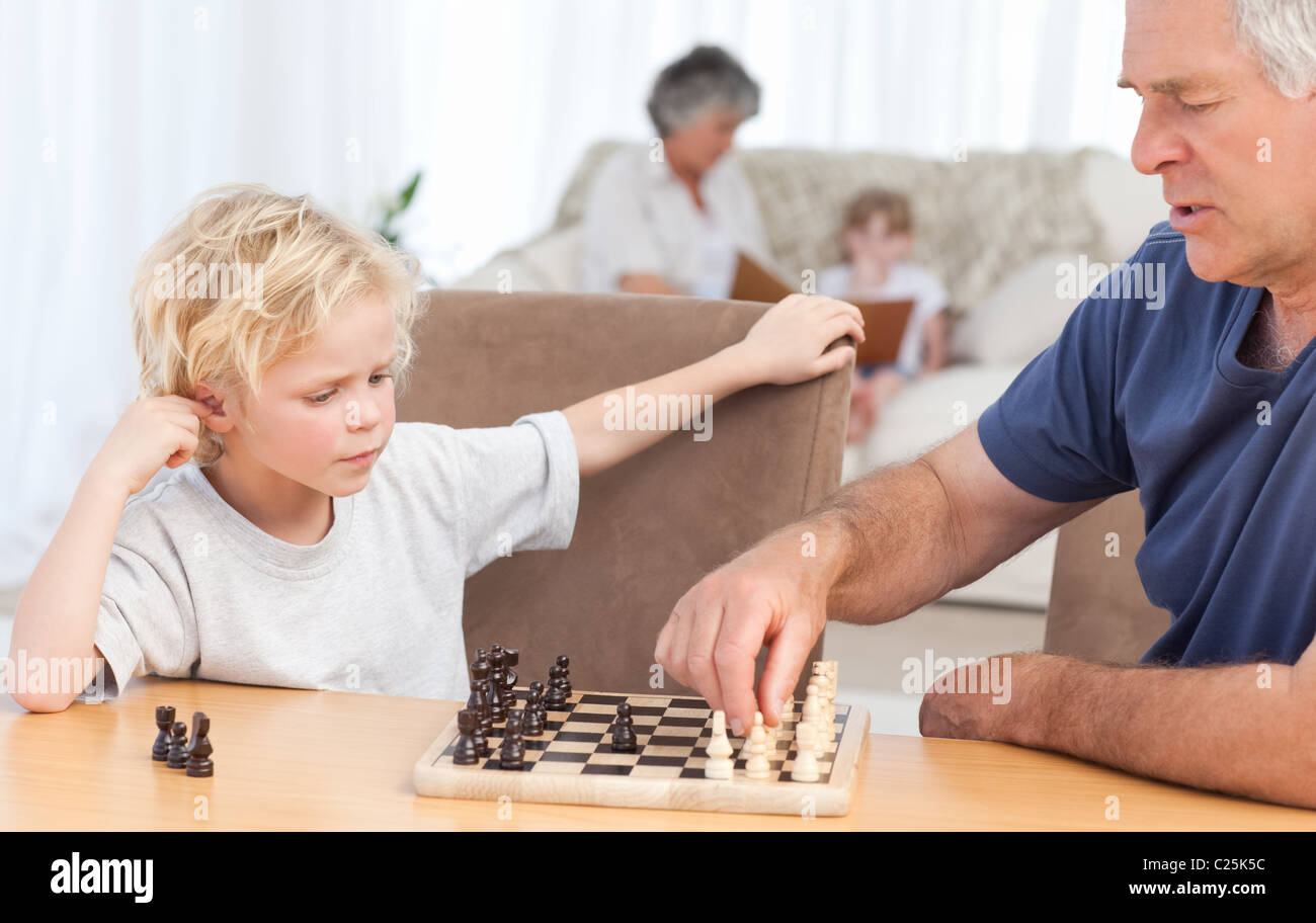 Young boy playing chess with his grandfather Stock Photo - Alamy