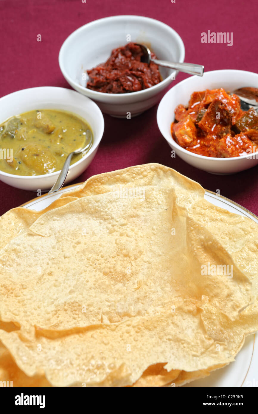 A plate of Indian pappadums with bowls of green mango, white lime and ...