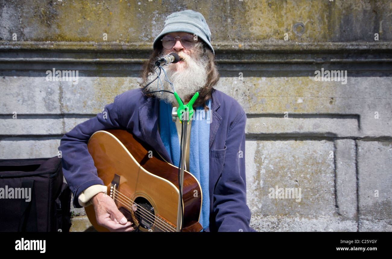 Man busking on his guitar, playing outside in the sun with hat on Stock ...
