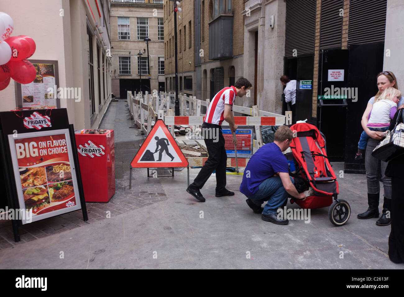 An employee from TGI Fridays sweeps the pavement outside as a family ...