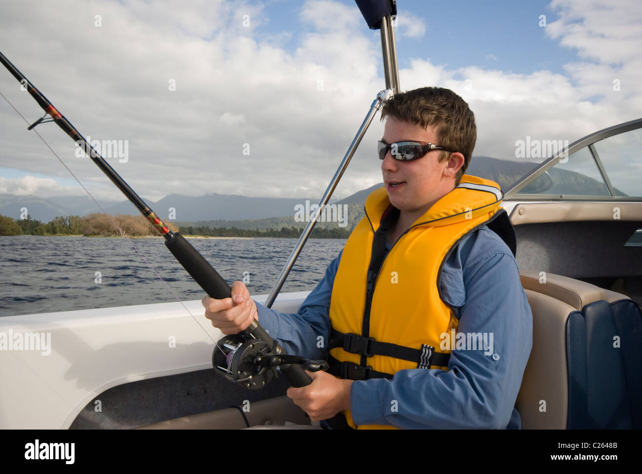 Teenage boy fishing from a power boat Stock Photo - Alamy