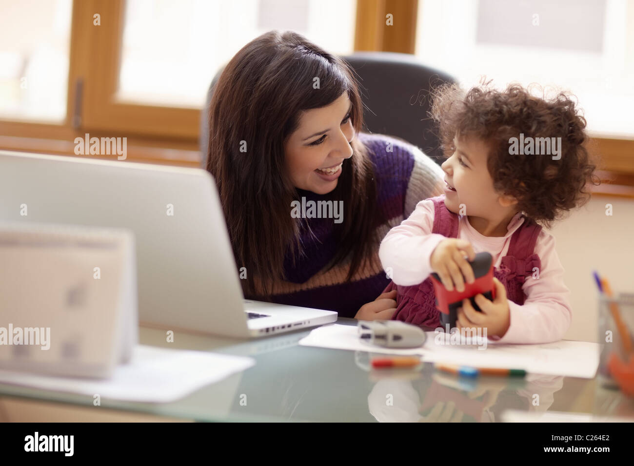 Mom and businesswoman working with laptop computer at home and playing ...