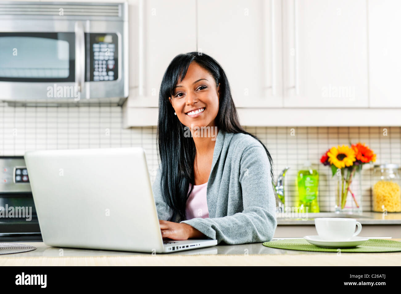 Smiling black woman using computer in modern kitchen interior Stock ...