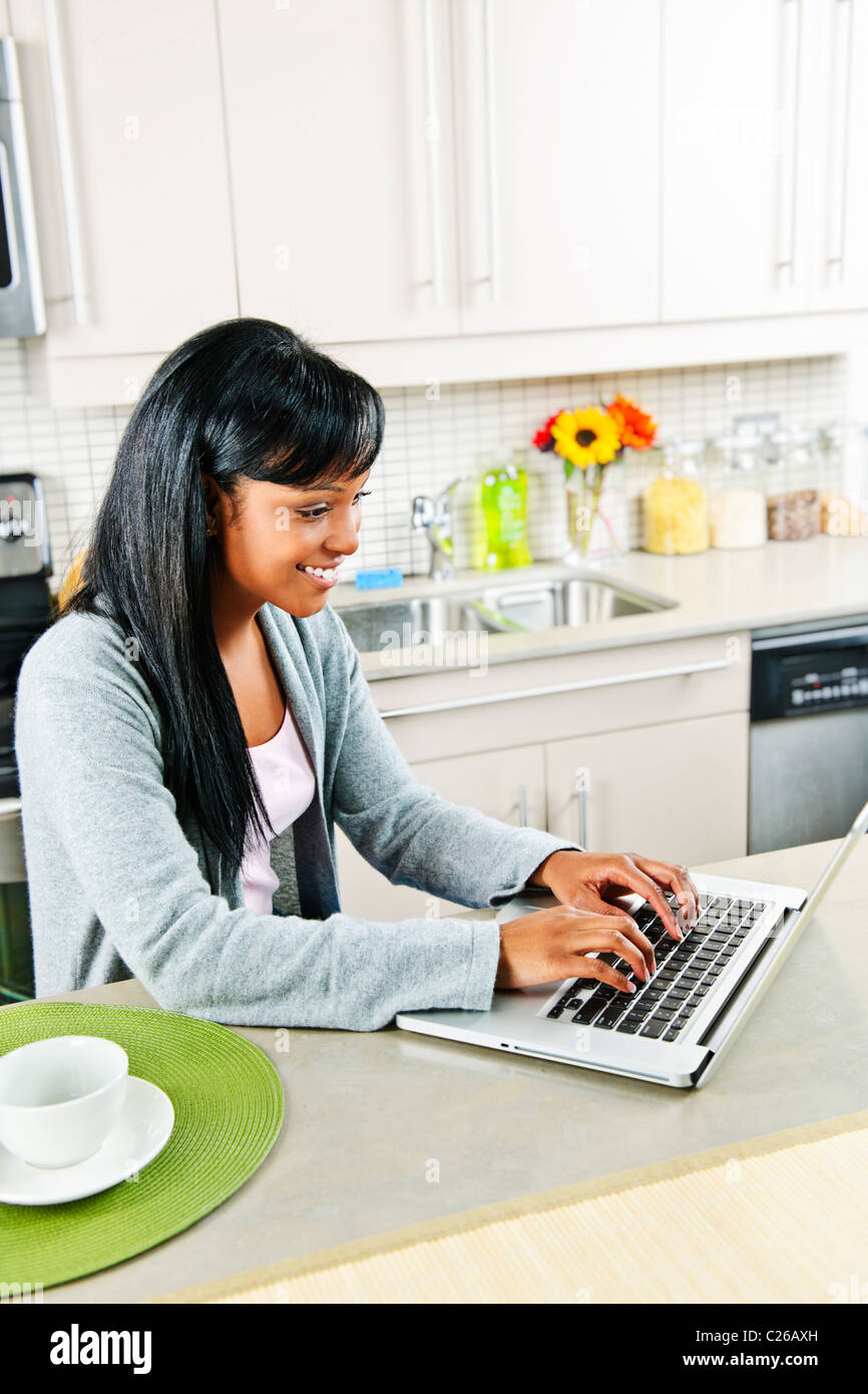 Smiling black woman using computer in modern kitchen interior Stock ...