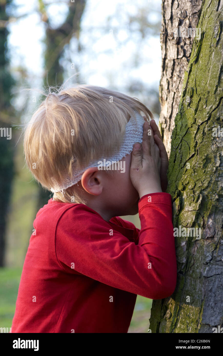 Child blond boy playing hide - and - seek in park Stock Photo - Alamy
