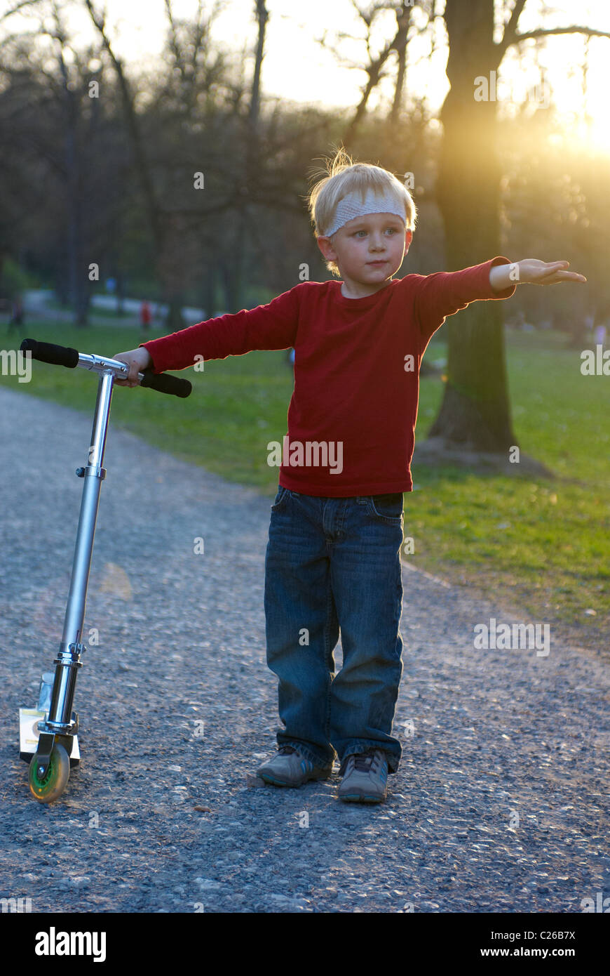 A young child blond boy on a scooter in park with injured head ...