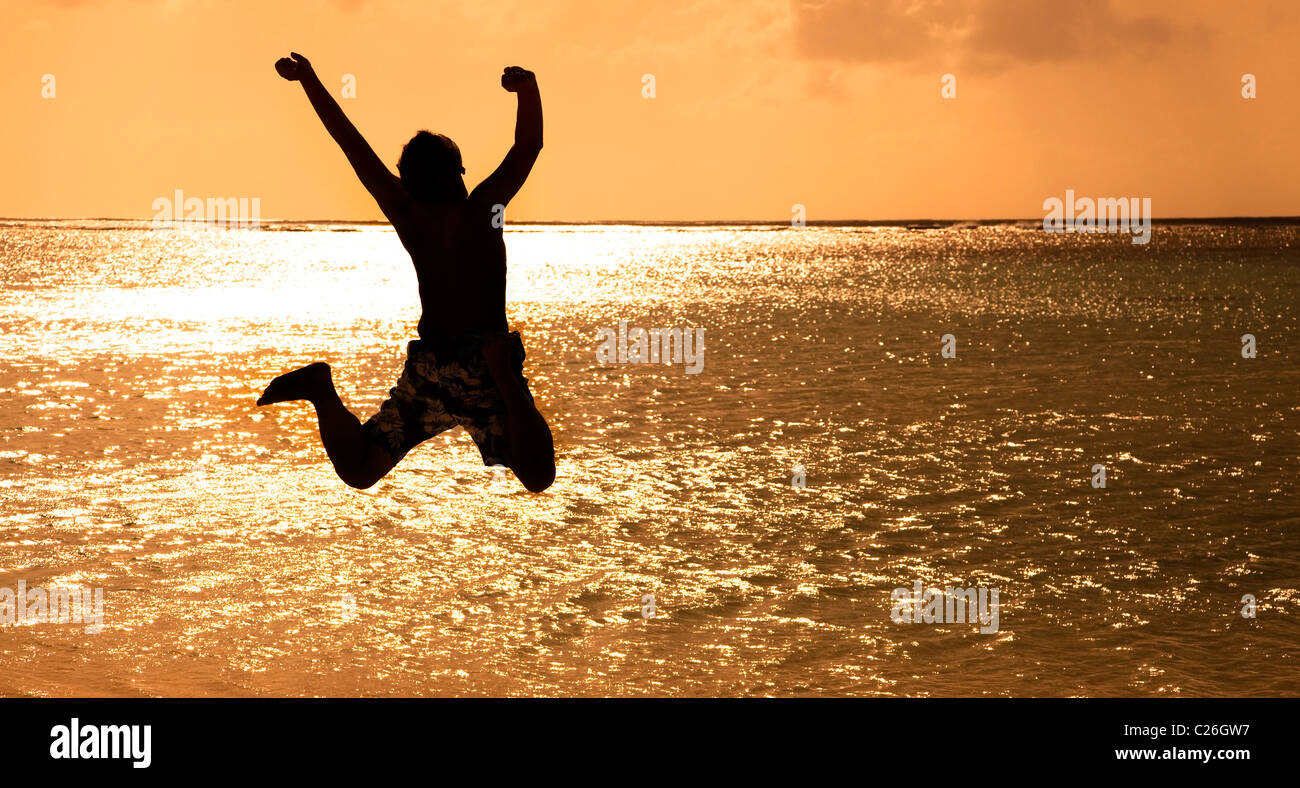 Happy Young man jumping on the beach at sunset Stock Photo - Alamy