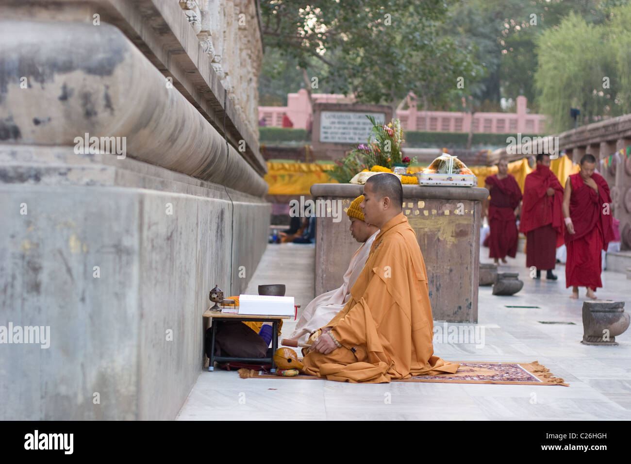 Two different Buddhist monks in yellow and white robes meditate just in ...