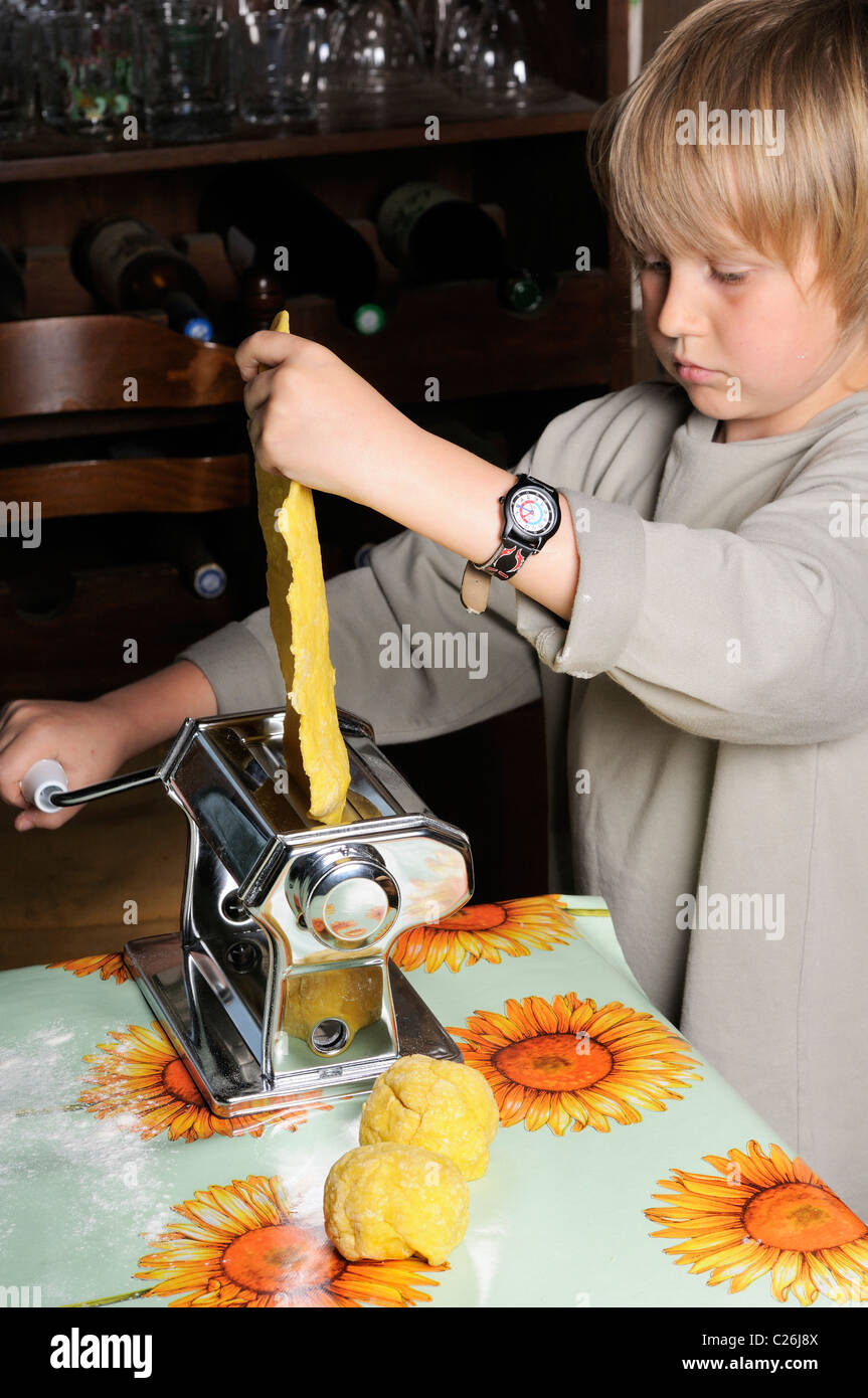 Stock photo of a young boy making fresh pasta with a pasta machine ...