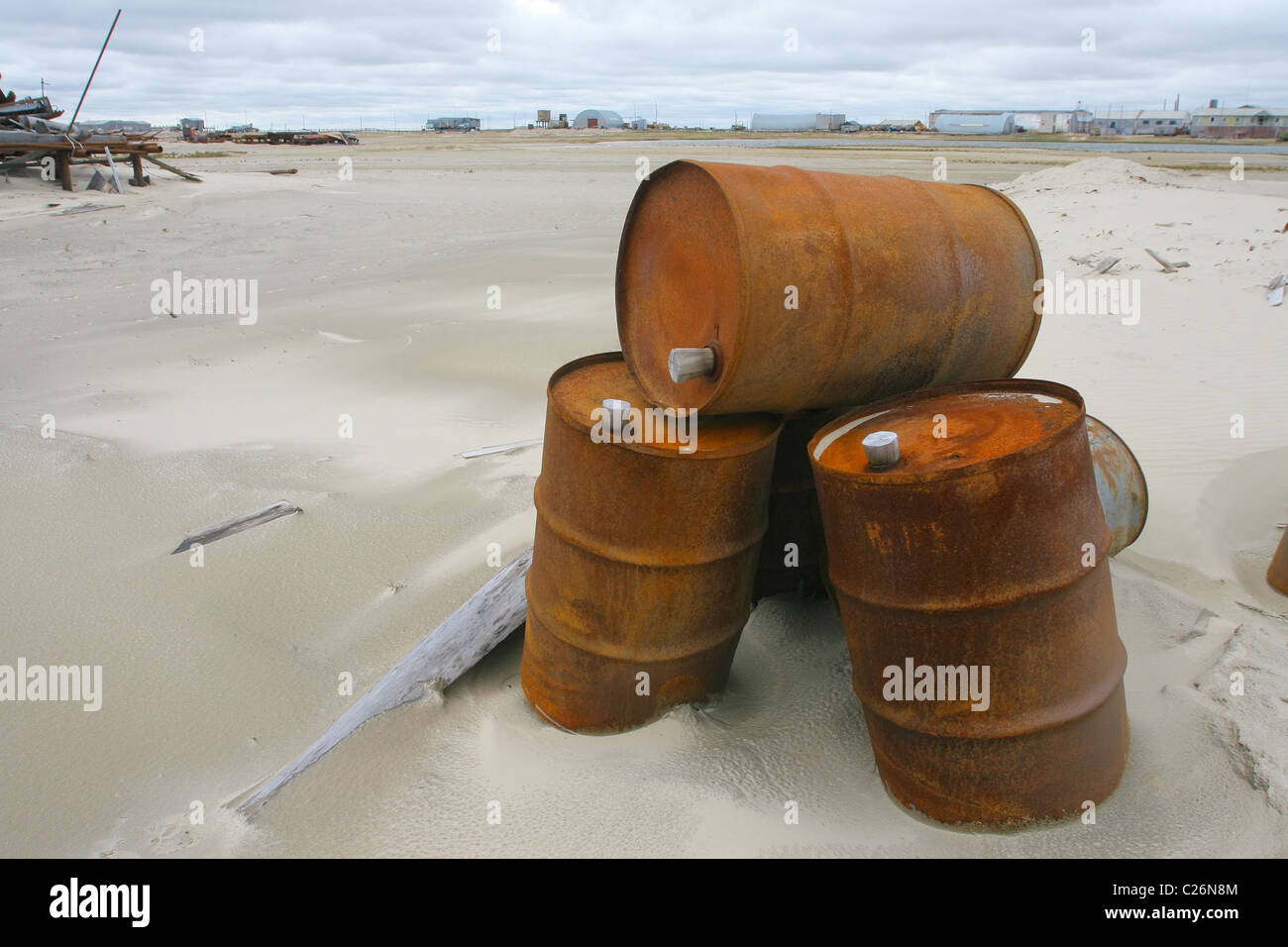 Rusty barrels with a wooden stopper stand on the sand. Yamal peninsula ...