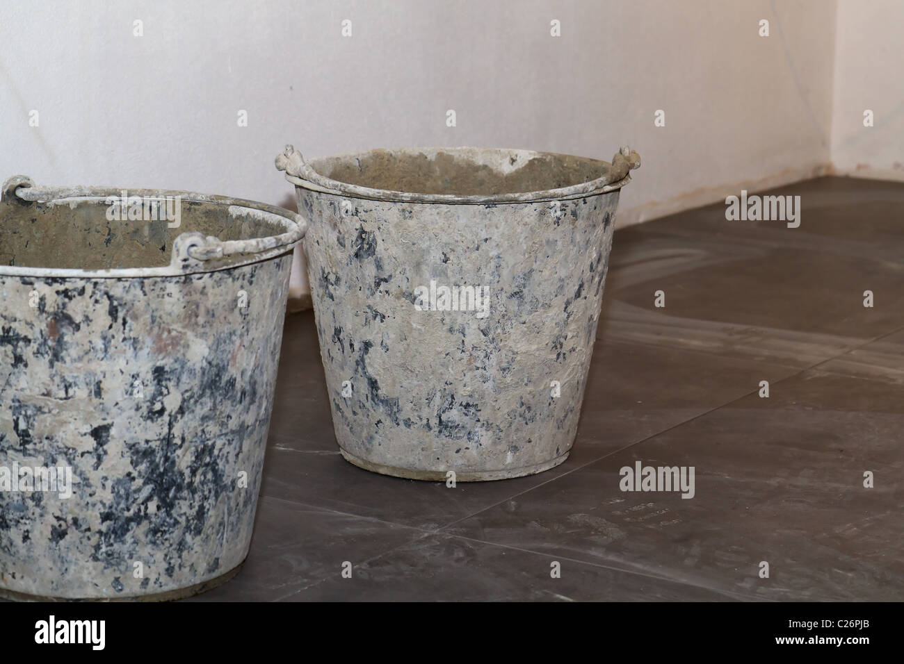 Two used cement buckets on new gray porcellanato tiles Stock Photo - Alamy