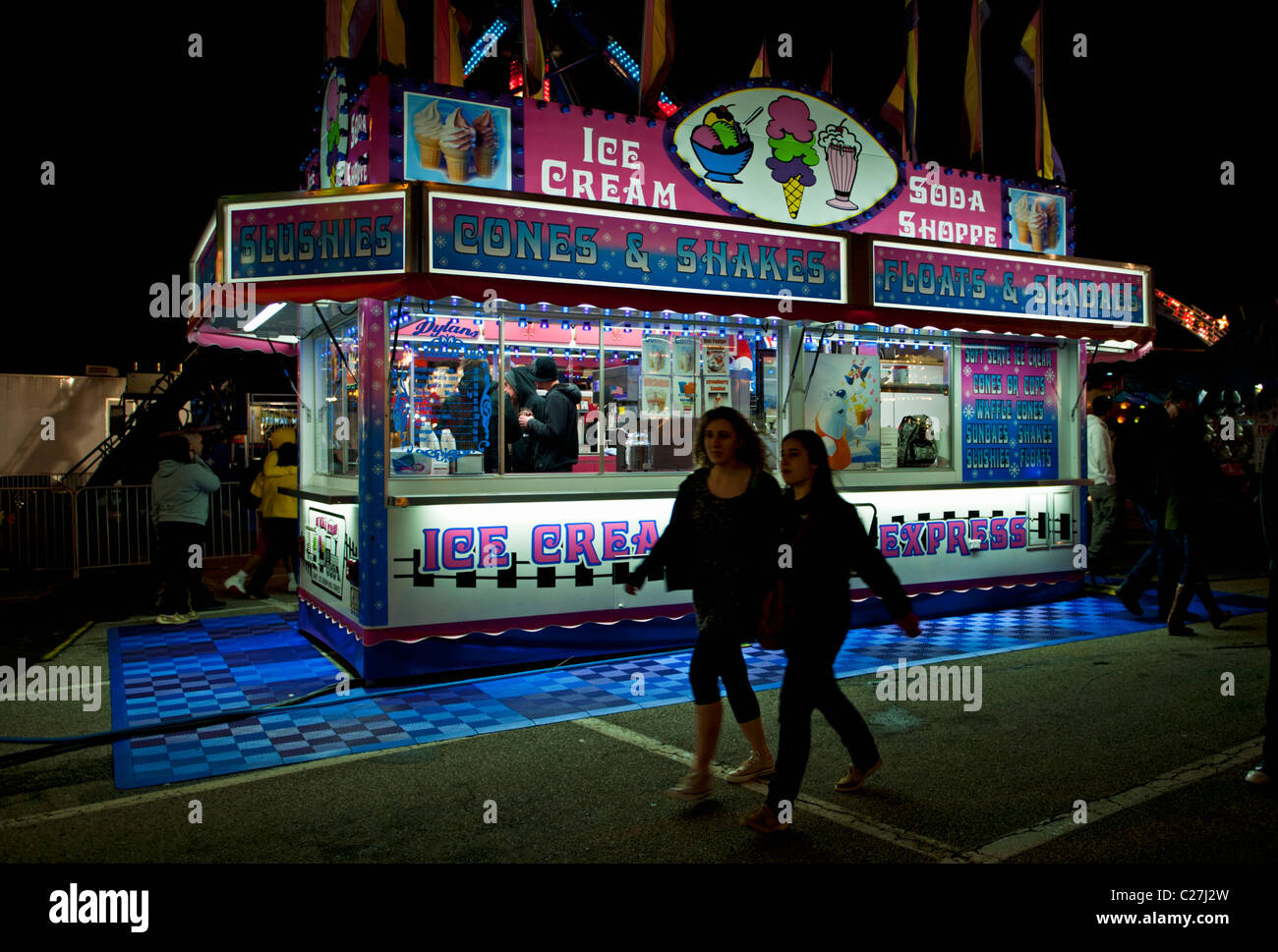 A night scene of a Colorful Ice Cream vendor at a local fair with two ...