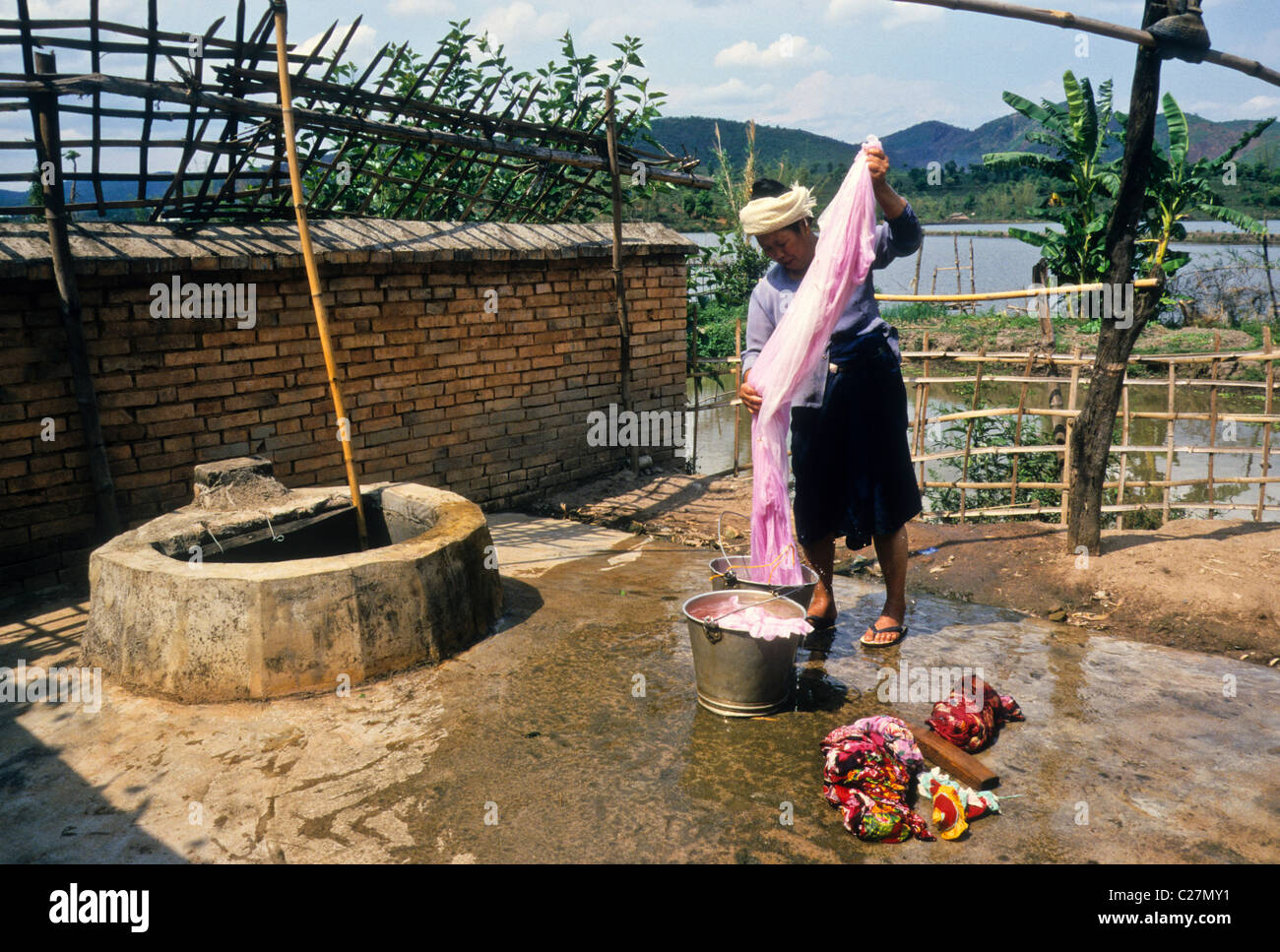 Shui Dai woman washing clothes at village well, Jingzheng ...