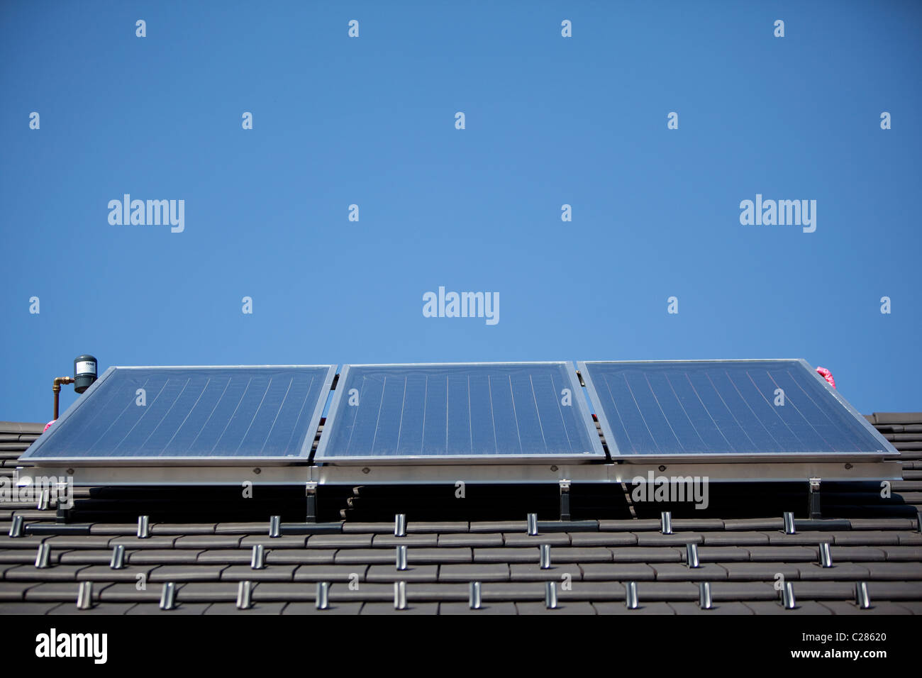 Three solar panels on a dark tiled roof Stock Photo - Alamy