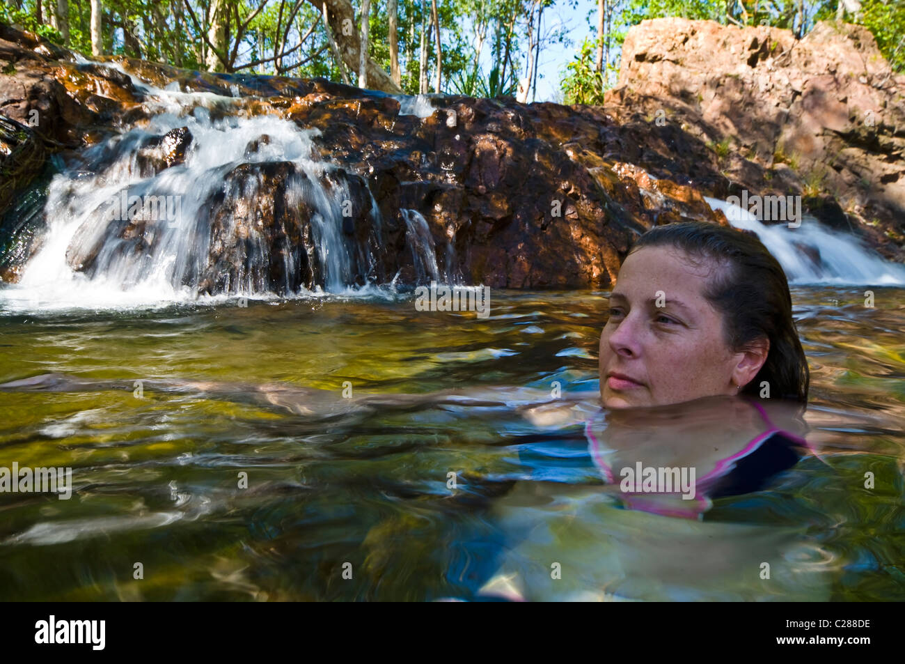 A woman swimming at the base of a tropical waterfall to stay cool Stock ...
