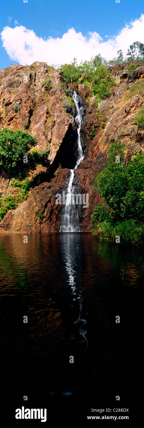 A waterfall tumbles down a rugged escarpment cliff face into a lagoon ...
