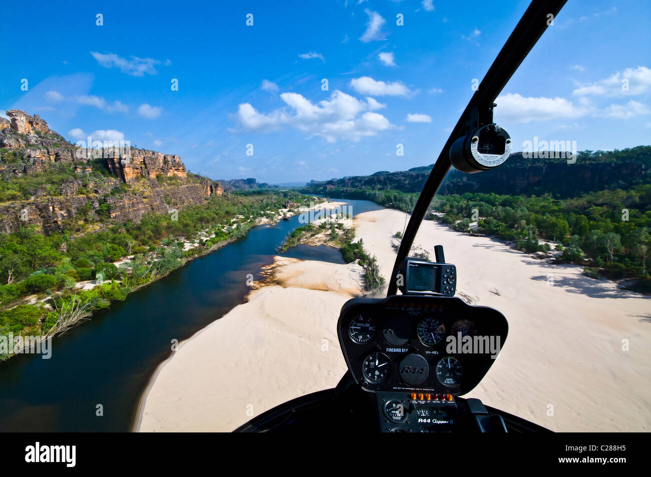 The view through a helicopter cockpit as it flies over a remote river ...