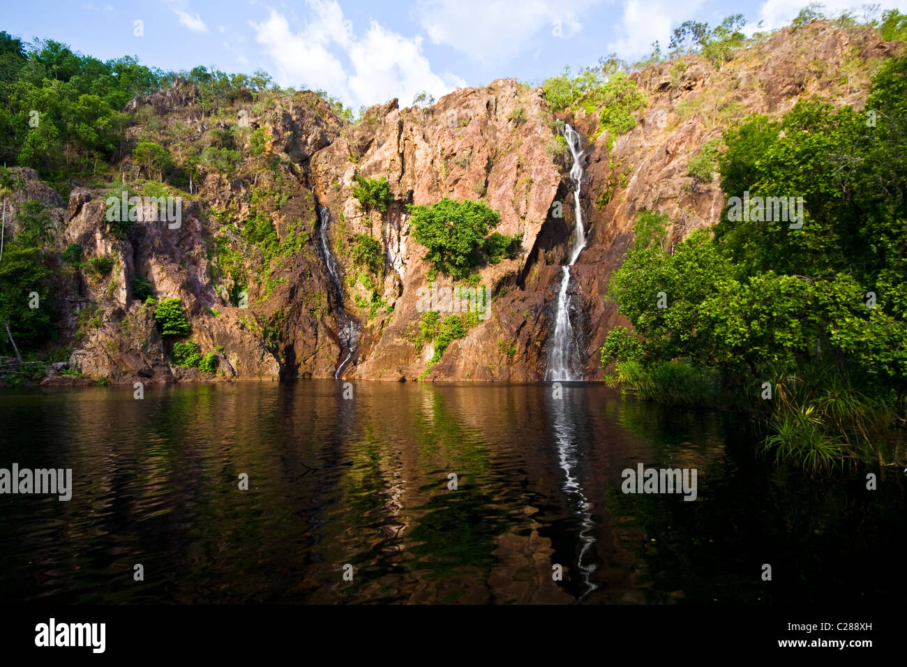 A waterfall cascades down a cliff face from a sandstone escarpment ...