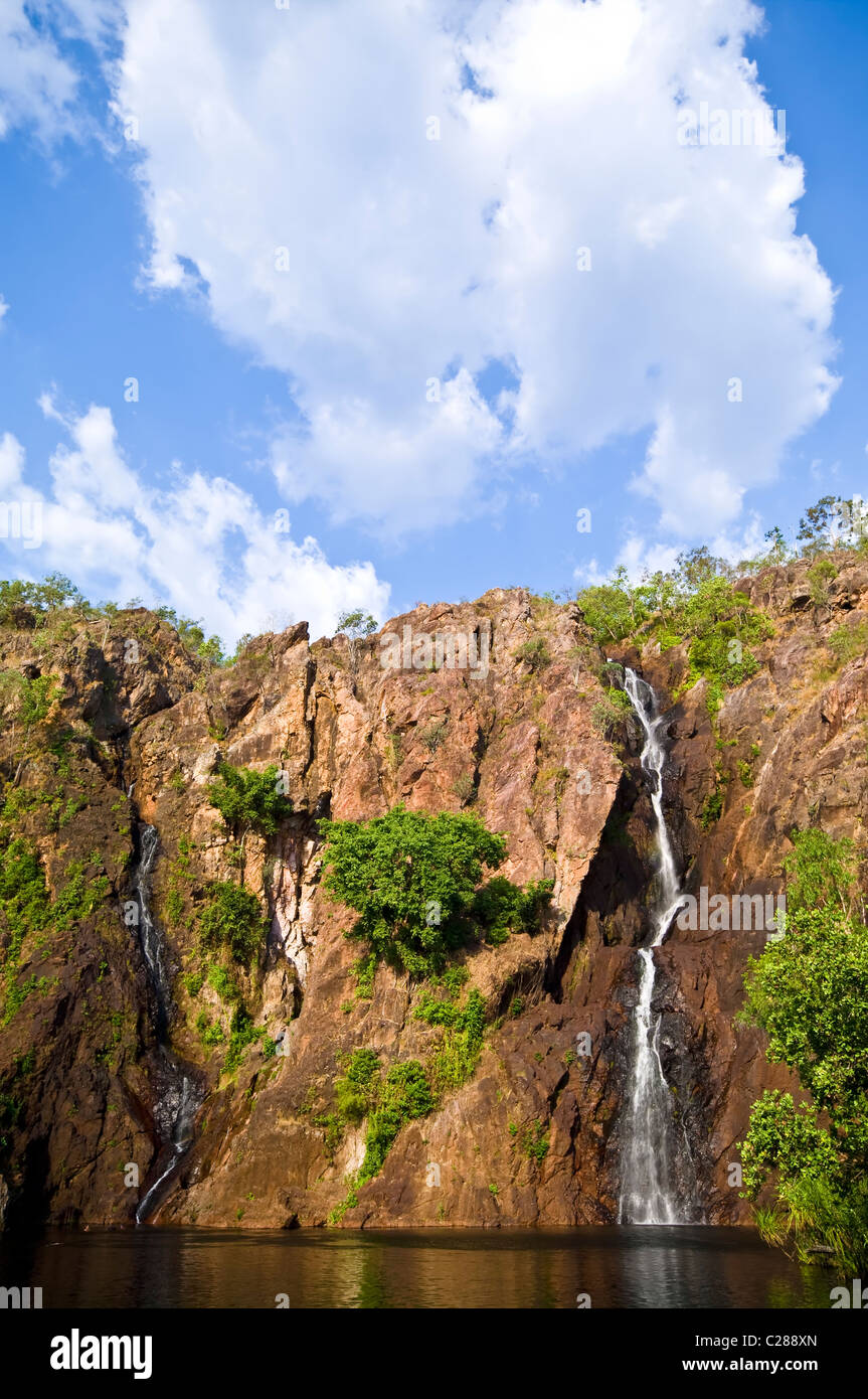 A waterfall cascades down a cliff face from a sandstone escarpment ...