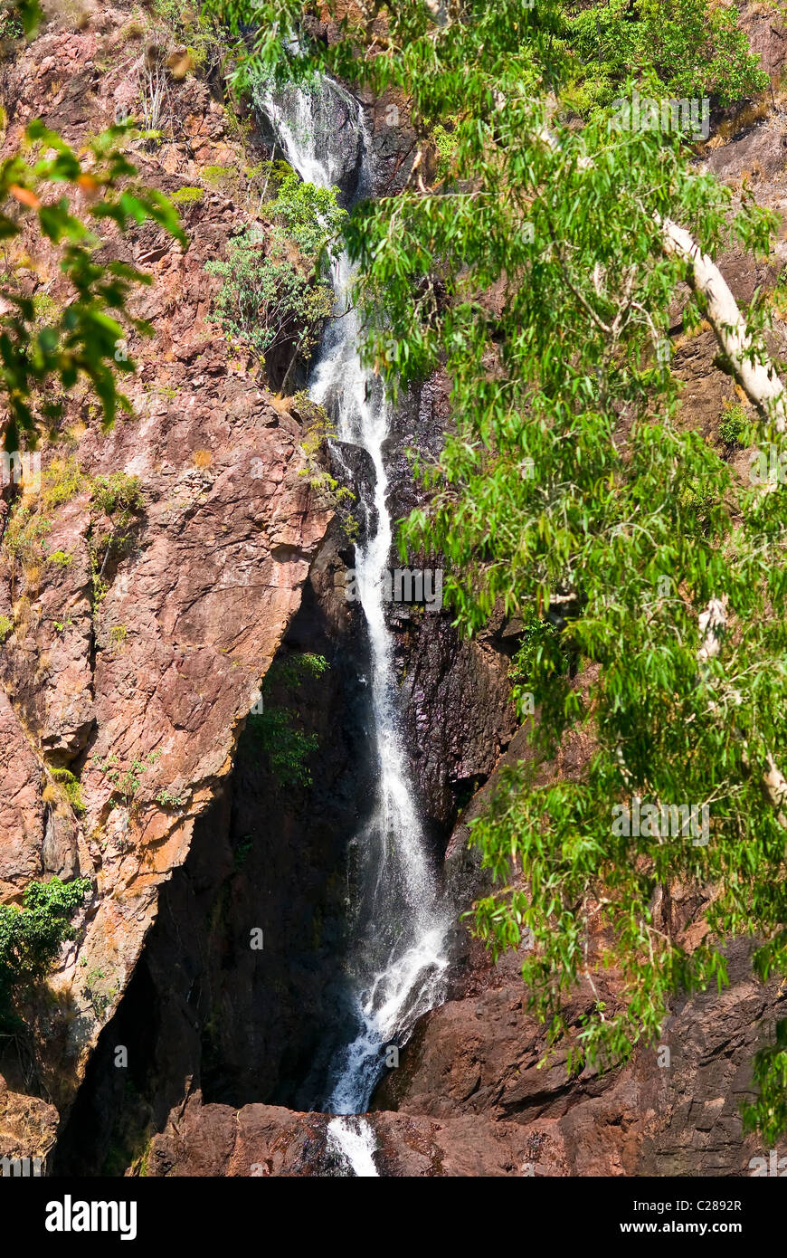 A waterfall cascades down a cliff face from a sandstone escarpment ...