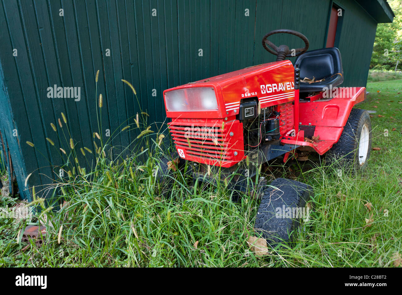 Riding tractor in tall grass against barn Stock Photo - Alamy