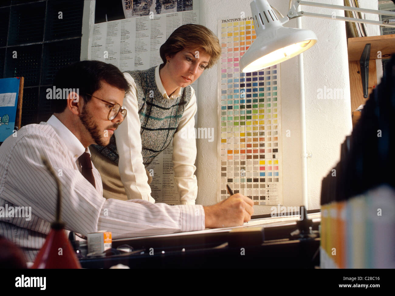 Male and female graphic designers working at a drafting table Stock ...