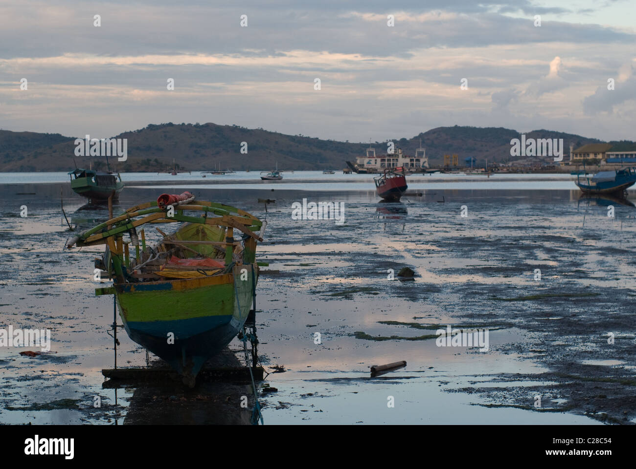 Wooden local fishing boats stay trapped on a ground in shallow water ...