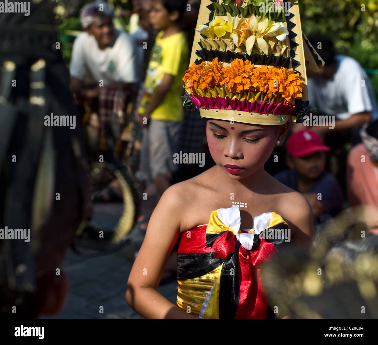 Balinese girl with tika brings a tower of offerings on her head for a ...