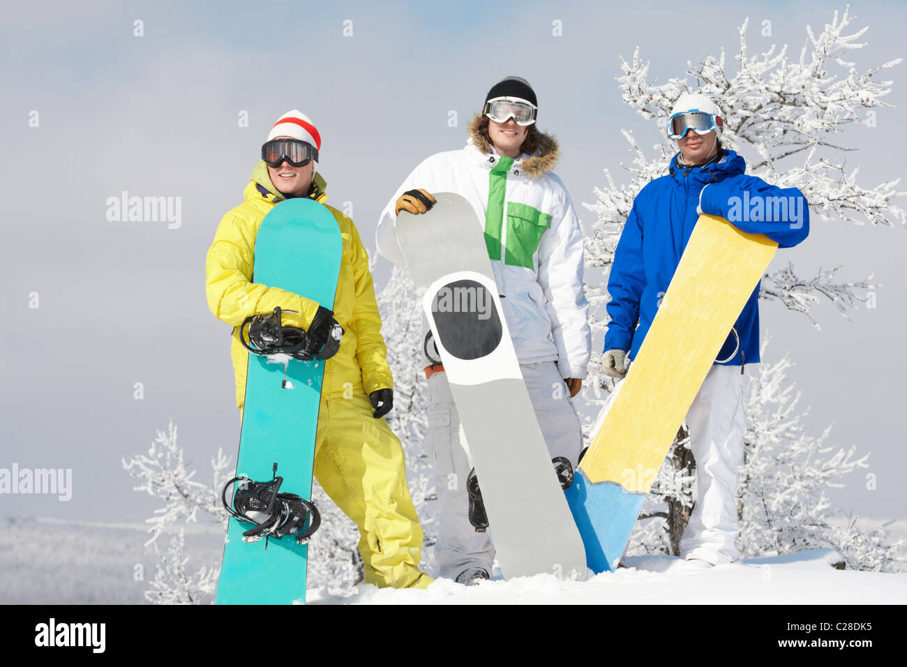 Portrait of handsome three snowboarders in googles standing on the hill ...