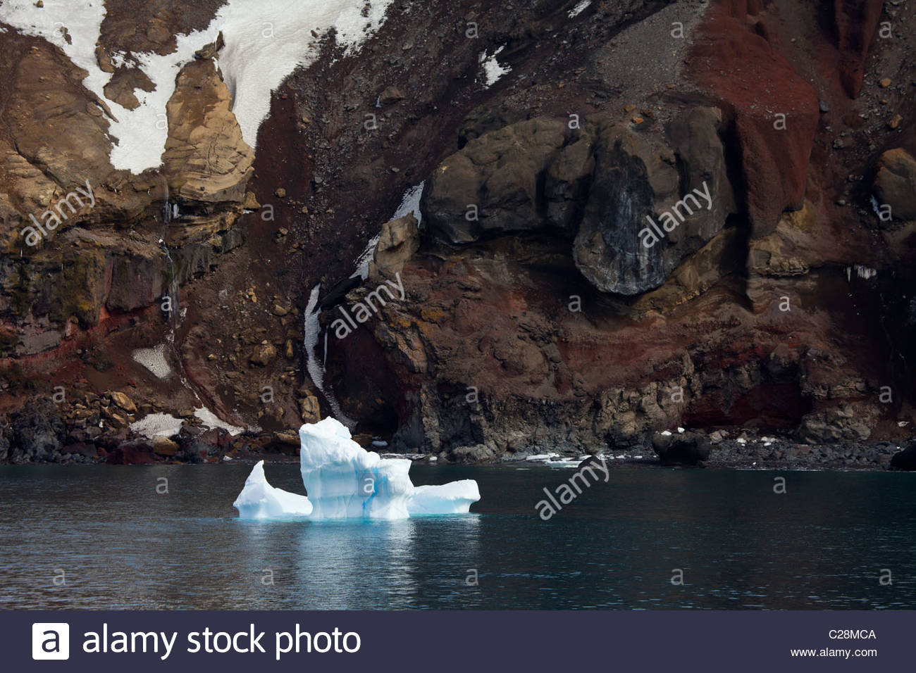 An iceberg floating past volcanic rock Stock Photo - Alamy