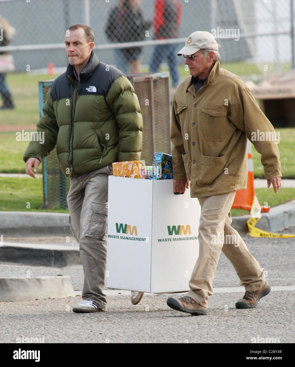 Harrison Ford carries a box of presents with a friend after attending a ...