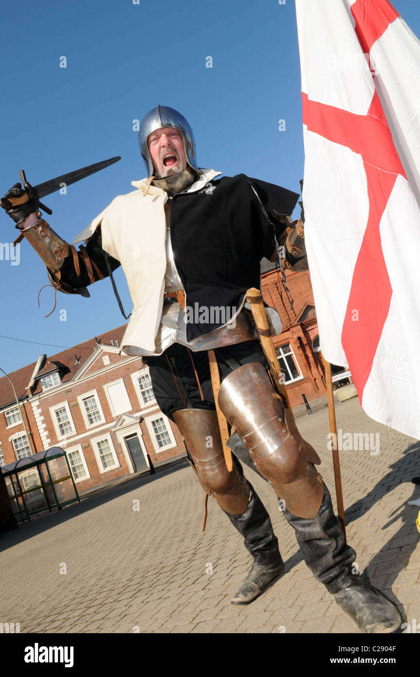 Man dressed as a English knight brandishing a sword and large flag of ...