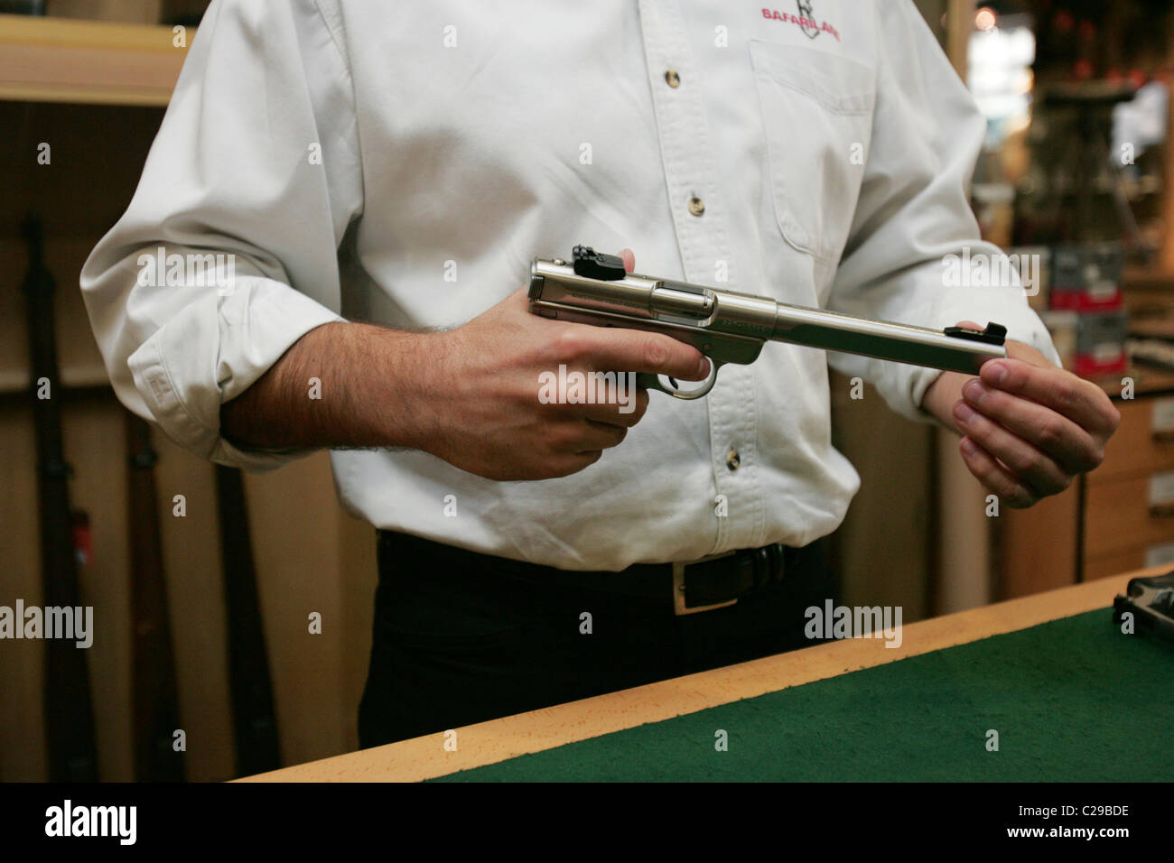 Gun shop owner showing a handgun to a customer Stock Photo - Alamy