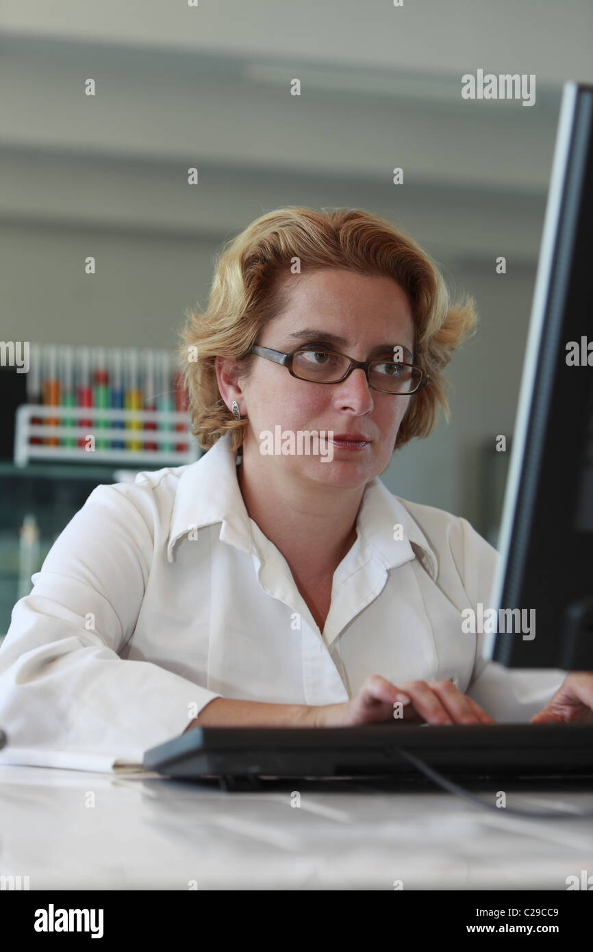 Female researcher working on a computer at her desk in a laboratory ...